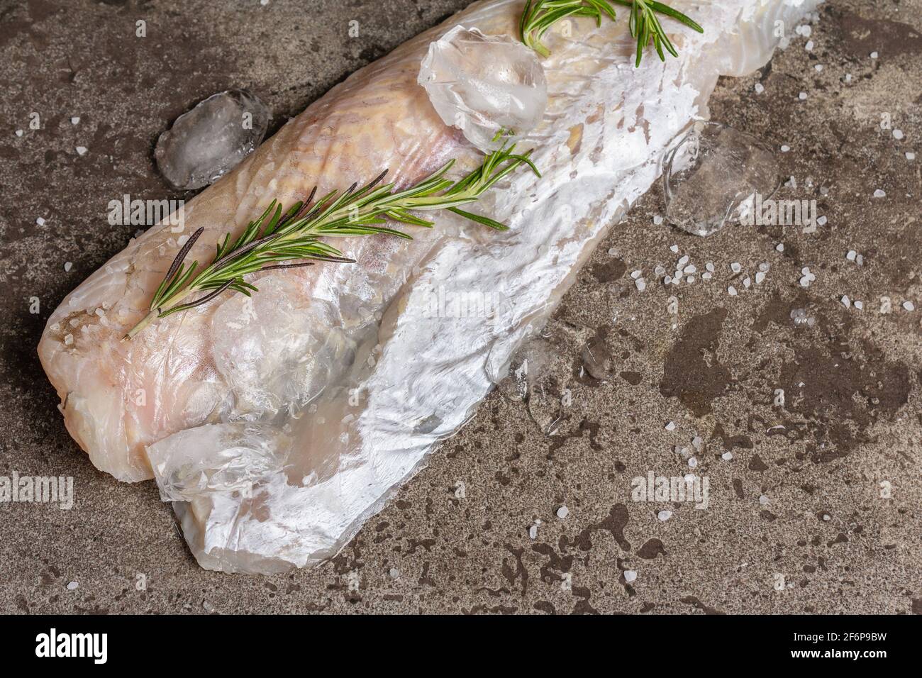 Raw frozen hake fillet with ice and fresh rosemary. Healthy food ...