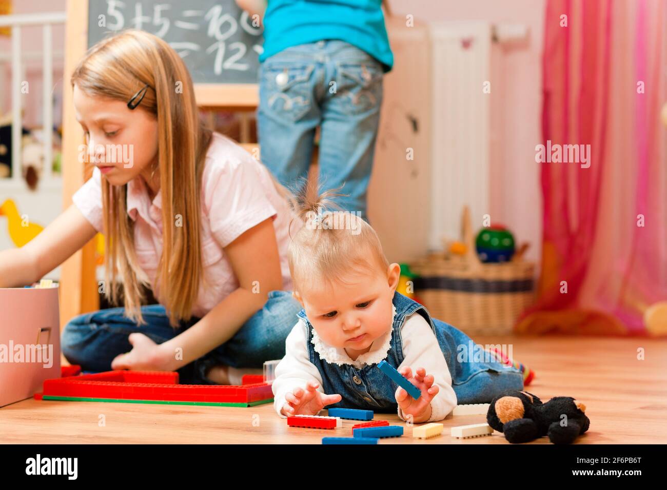 Children - sisters - playing at home; one child is still a baby Stock ...