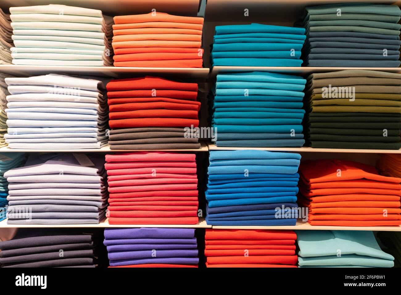 Multicolored shirts folded and sorted by colour ranges. Market place ...