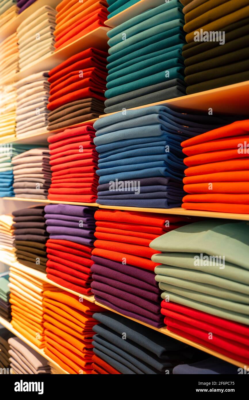 Vertical photo of multicolored clothes folded in a shelve and sorted by ...