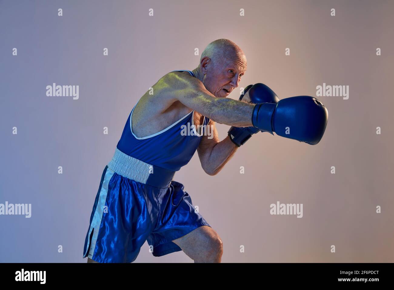 Senior man wearing sportwear boxing isolated on gradient studio ...