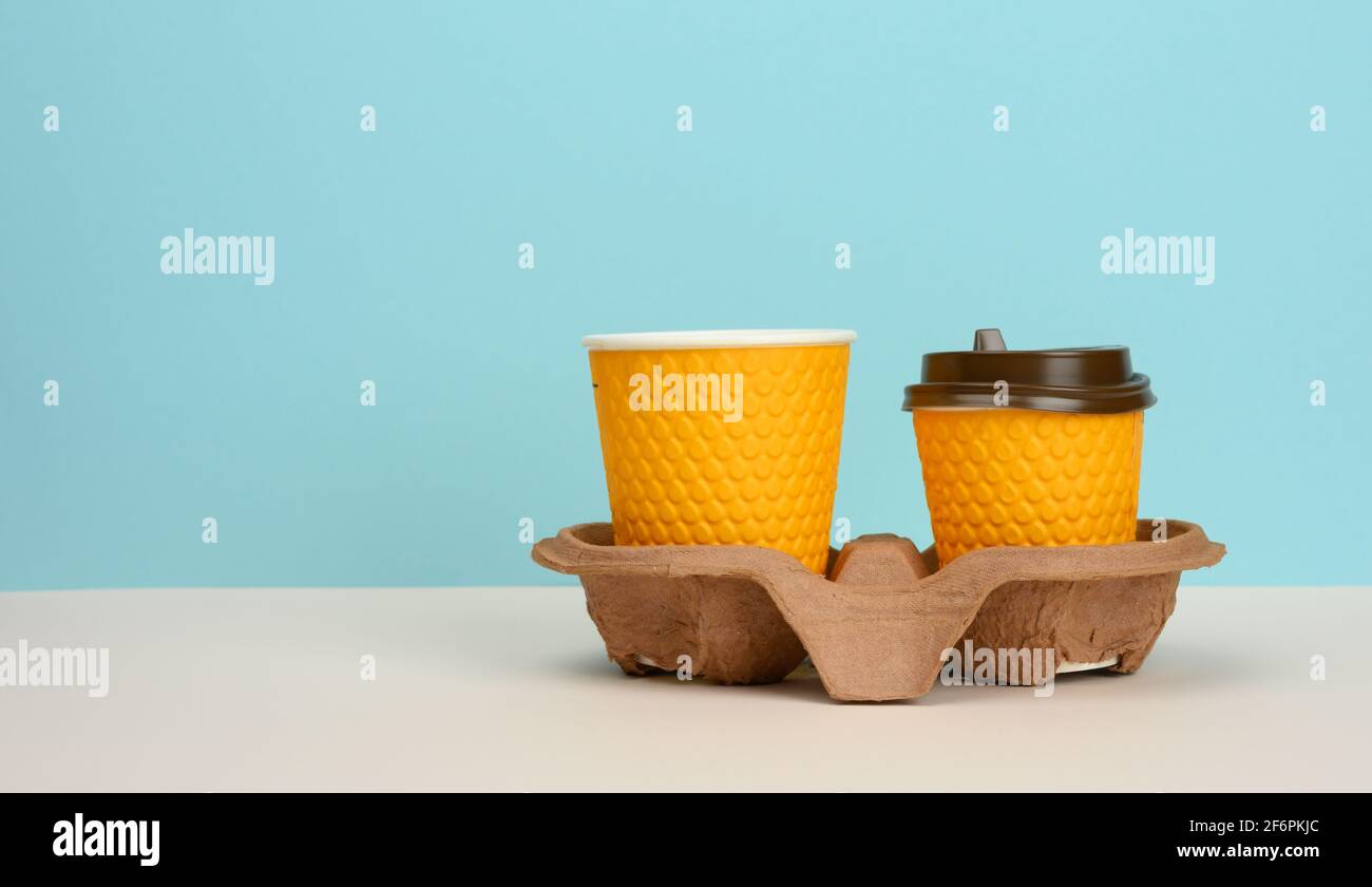 two orange paper disposable cups stand in a brown tray on a blue ...