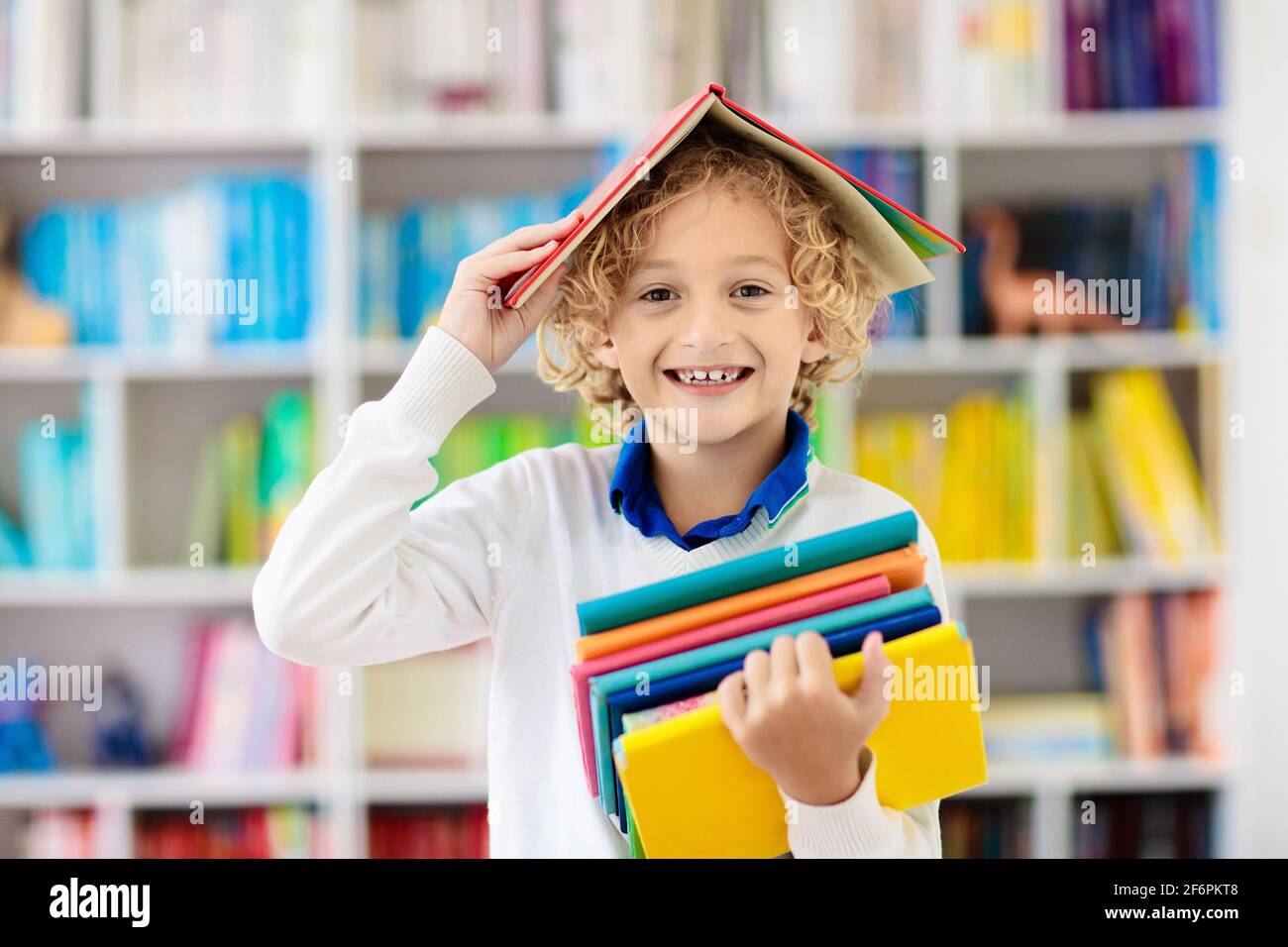 Child reading book. Kids read. Little boy at a colorful bookshelf doing ...