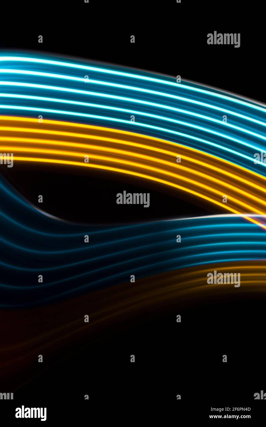 Yellow and blue light curve lines on a black background Stock Photo - Alamy