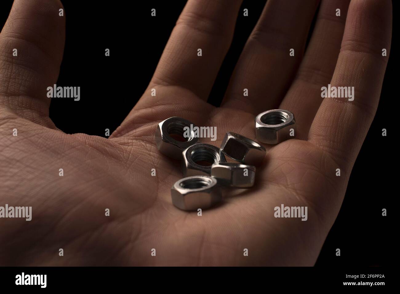 screw-nuts in hands on a black background Stock Photo - Alamy