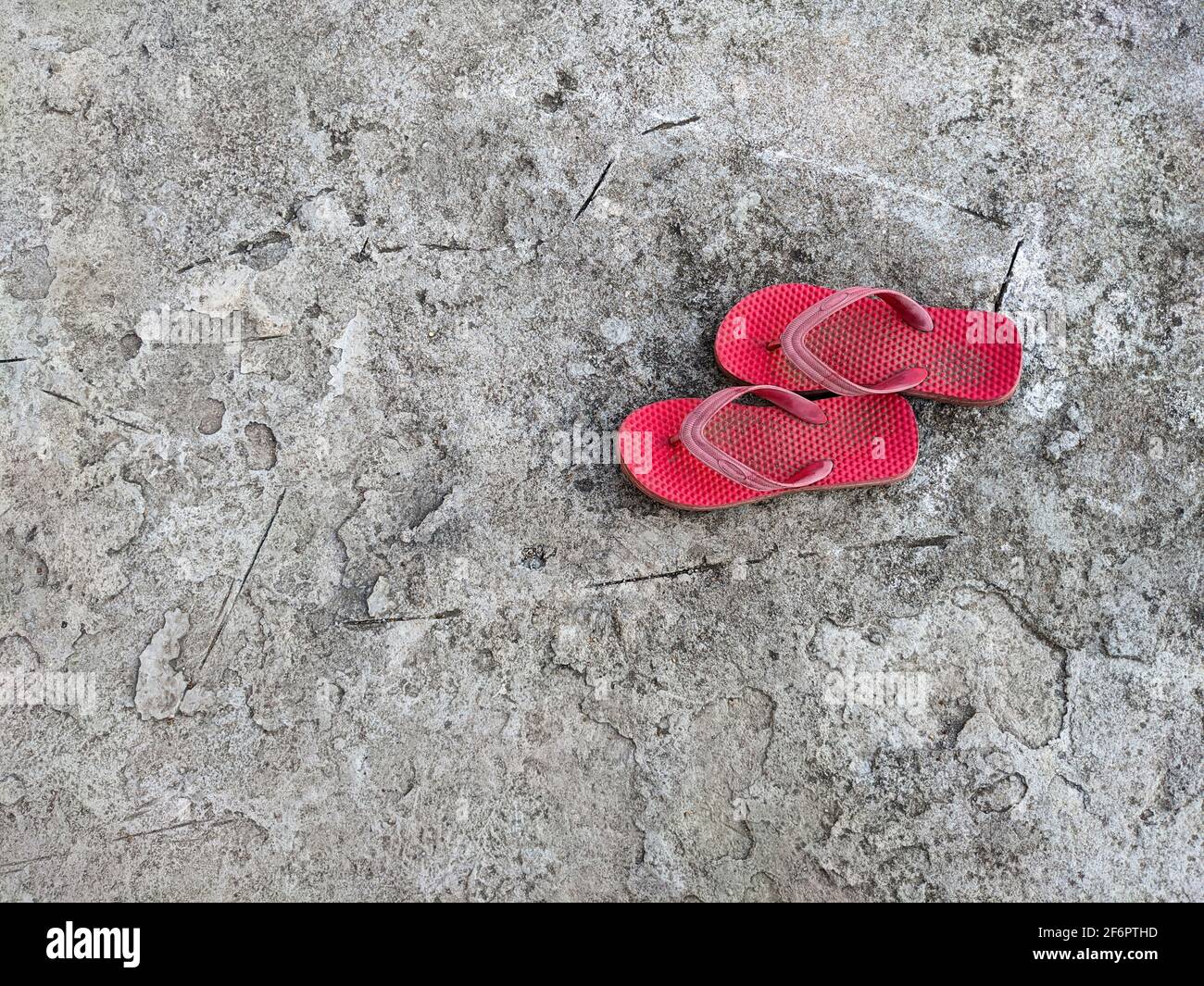 Top view of red rubber slipper isolated on concrete texture background ...