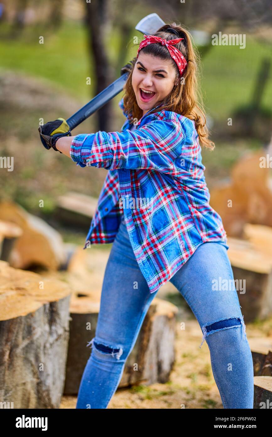 young woman with an ax in her hand rests after breaking beech logs ...