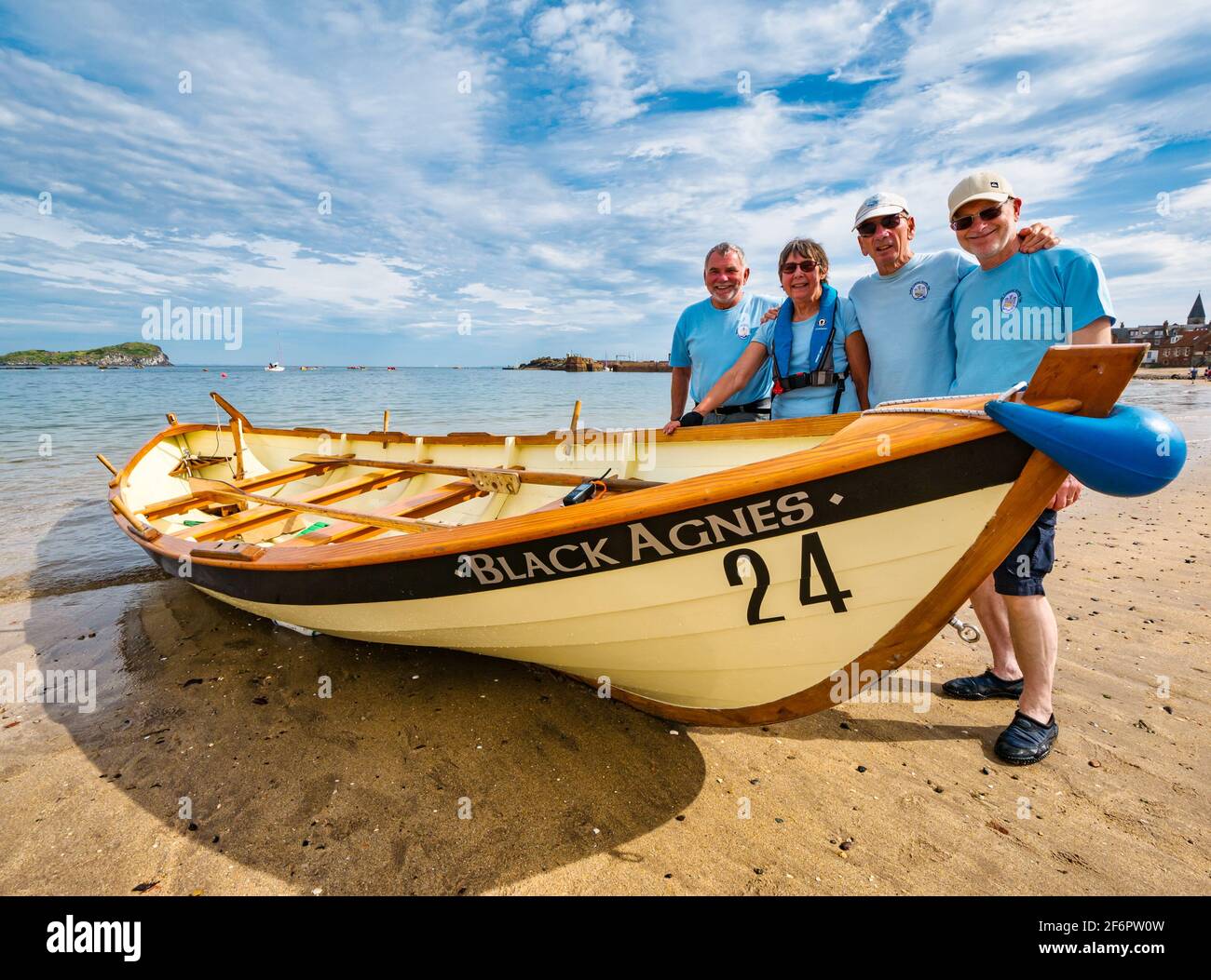 Dunbar coastal rowing club crew with St Ayle's wooden rowing boat skiff on beach during regatta ...