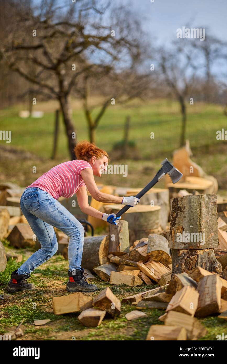 Strong woman splitting beech logs for firewood Stock Photo - Alamy