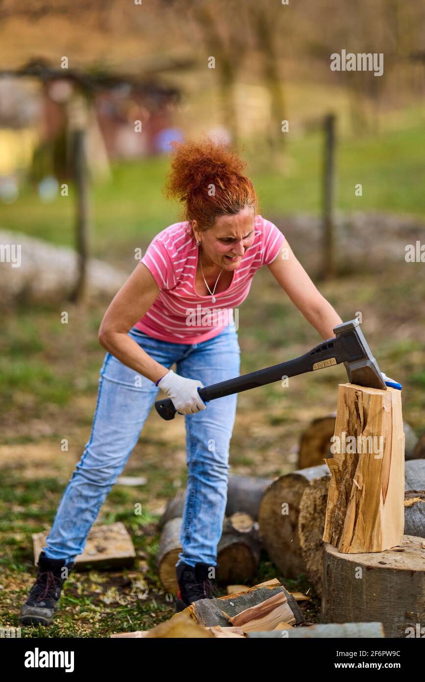 Strong woman splitting beech logs for firewood Stock Photo - Alamy