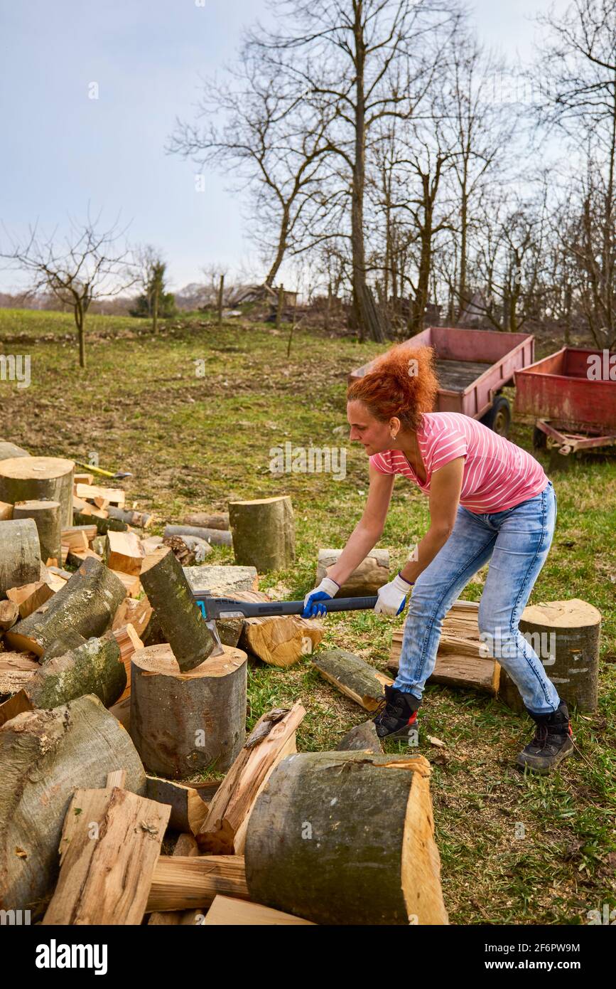 Strong woman splitting beech logs for firewood Stock Photo - Alamy