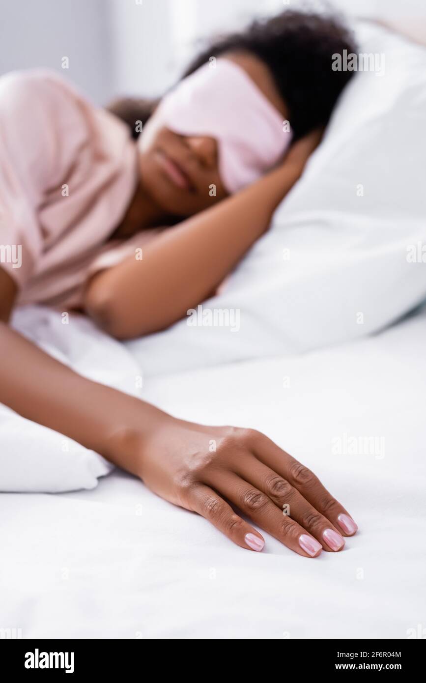 Hand of african american woman sleeping on white bedding on blurred ...