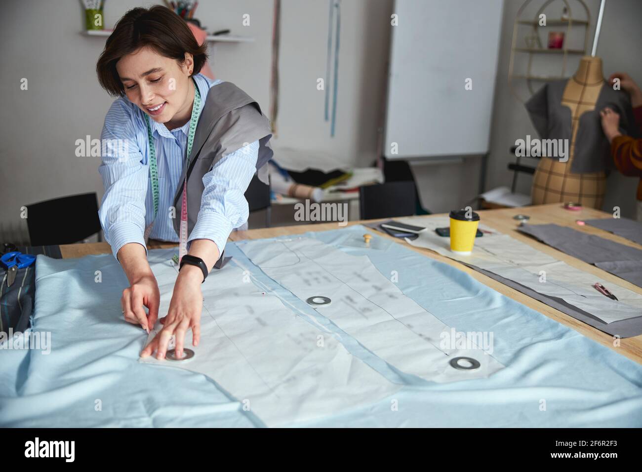Dressmaker painting lines on fabric with a smile Stock Photo - Alamy
