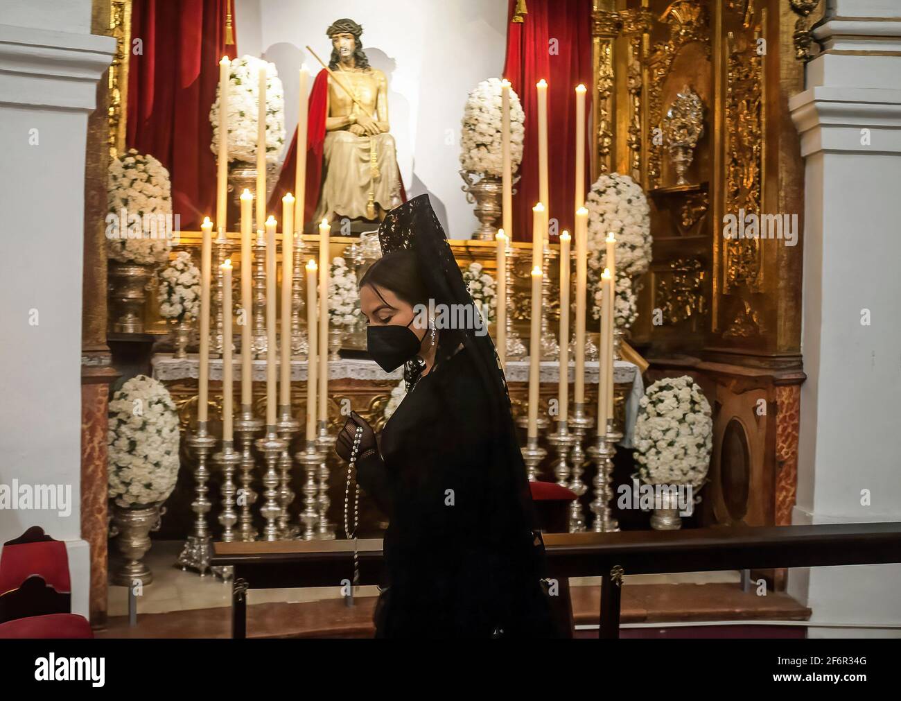 A woman wearing a mantilla dress and face mask Is seen praying inside ...