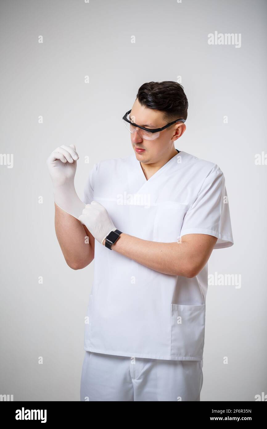 The specialist doctor puts rubber gloves on his hands before the ...