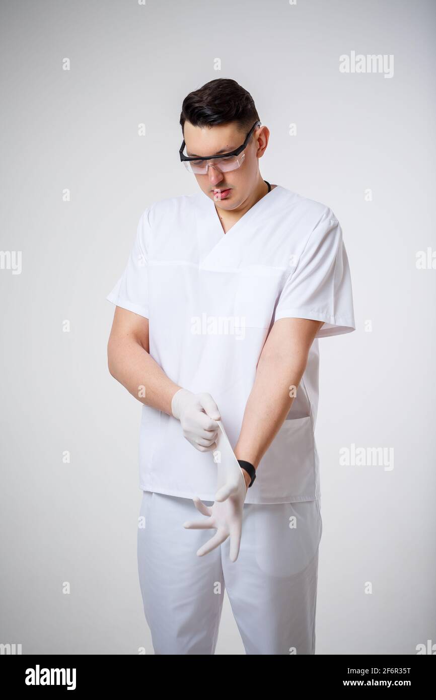 The specialist doctor puts rubber gloves on his hands before the ...