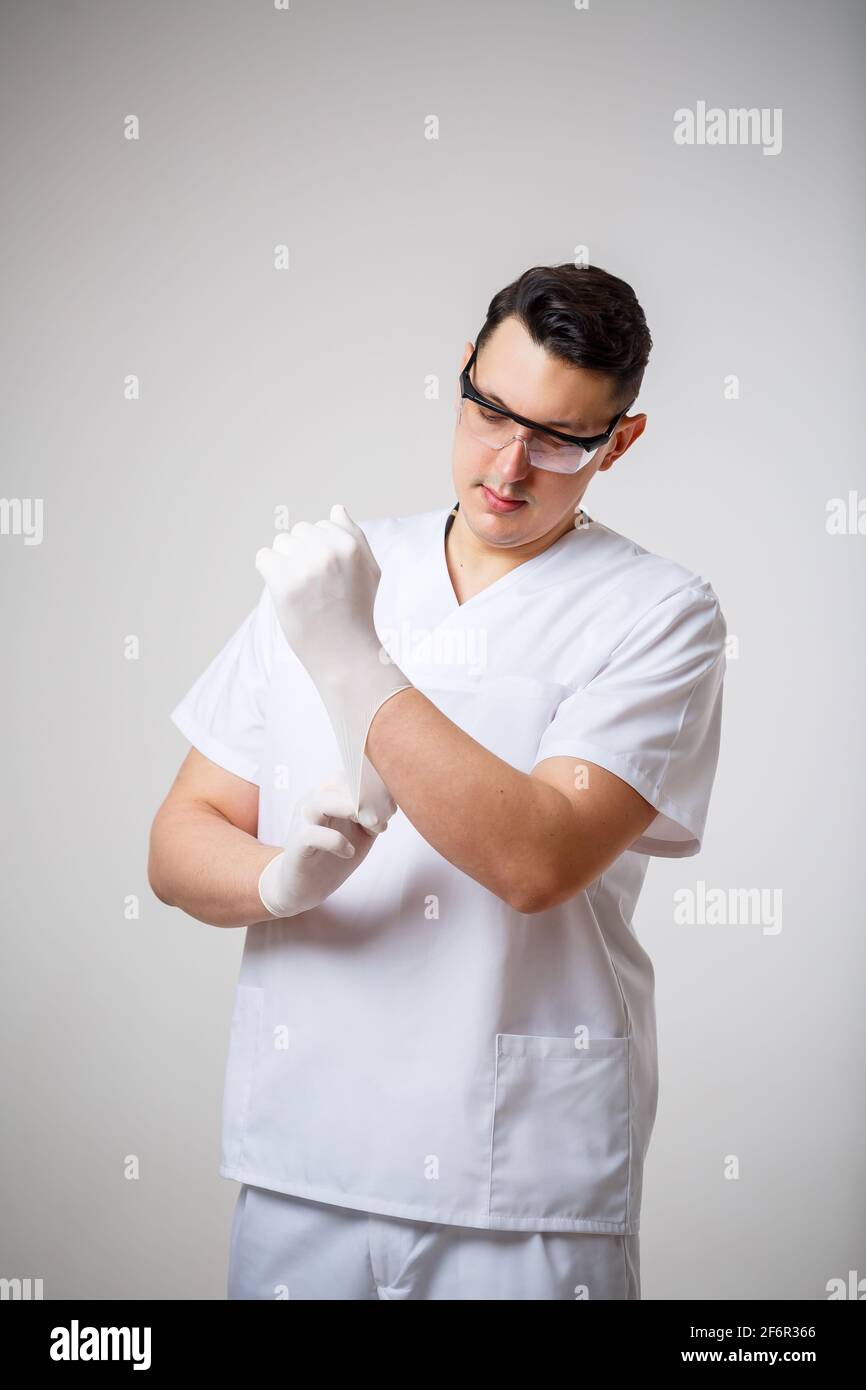The specialist doctor puts rubber gloves on his hands before the ...