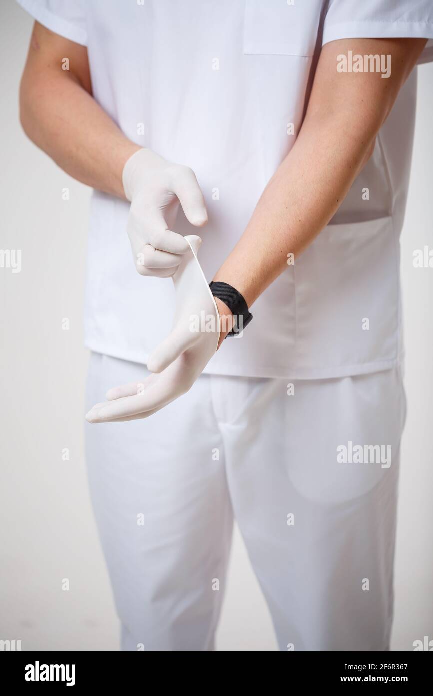 The specialist doctor puts rubber gloves on his hands before the ...