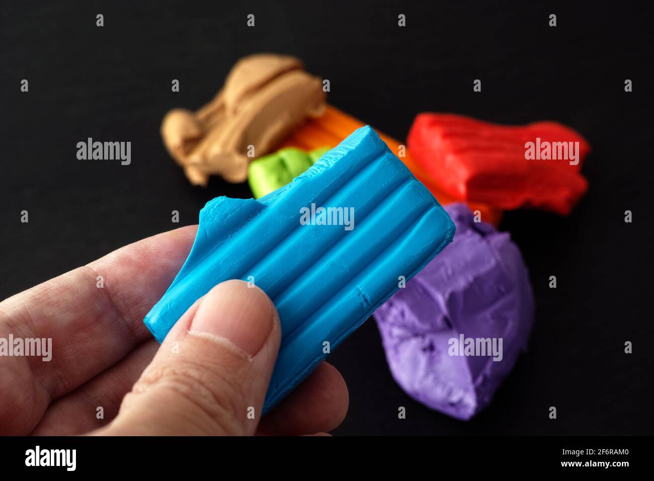 A man holding a piece of polymer clay in his hand. Low key. Close up ...