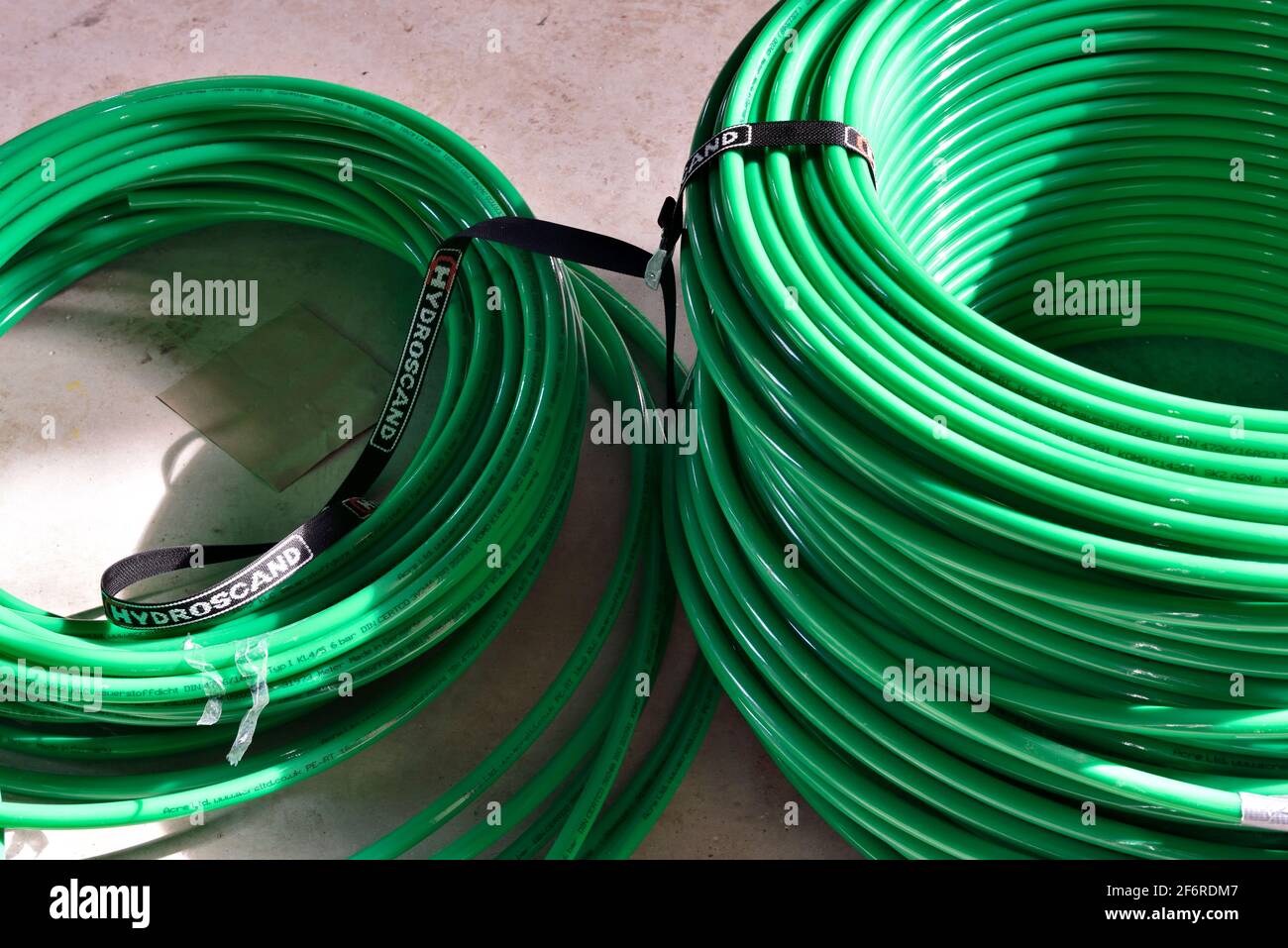 Coils of green plastic underfloor heating pipe Stock Photo - Alamy