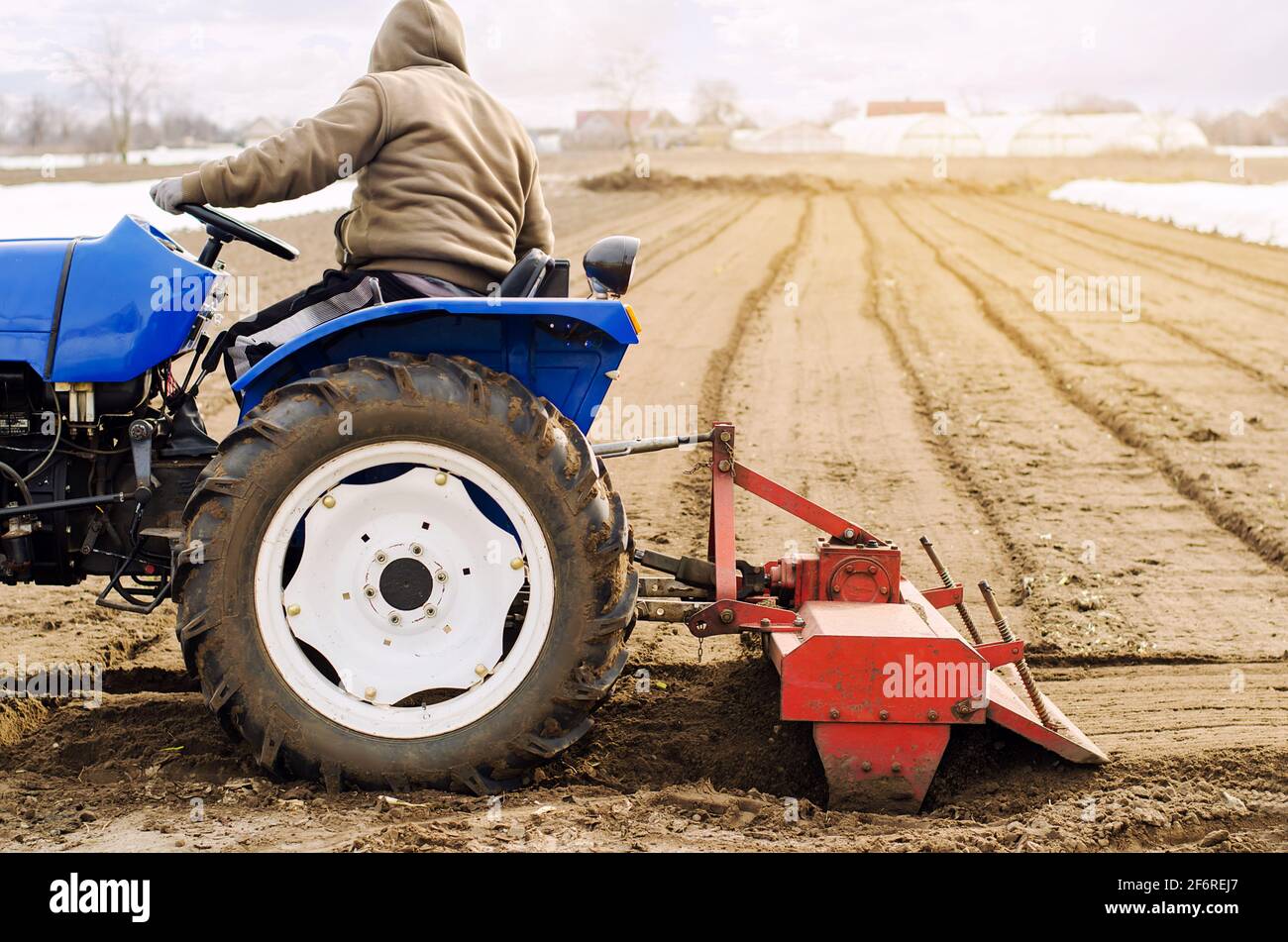 Farmer on a tractor with milling machine loosens, grinds and mixes soil ...