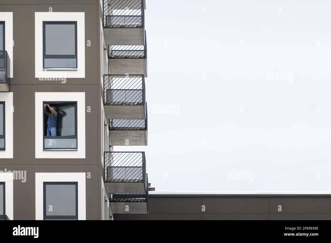 Carpenter installing a window high up in an apartment block. Contractor ...