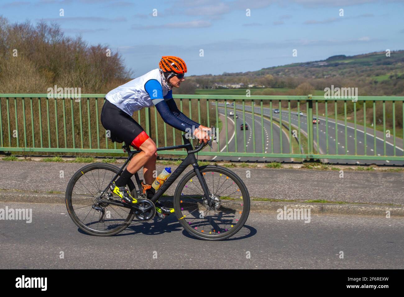 Male cyclist riding sports road bike on countryside route crossing ...