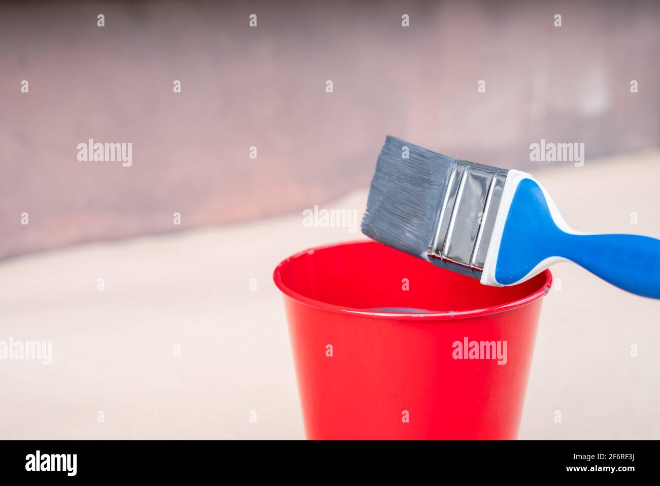 Paint brush and a bucket with paint next to a building exterior wall ...