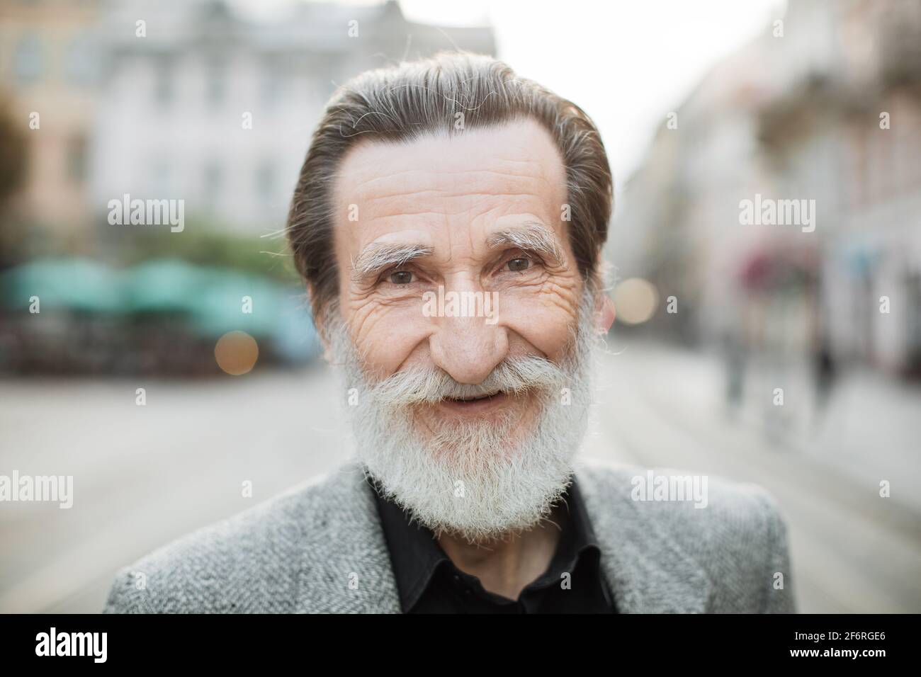 Portrait of smiling grey-haired man dressed in elegant clothes posing ...