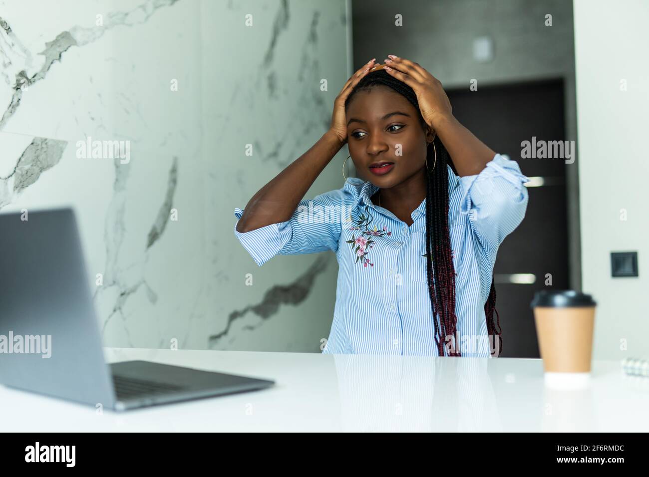 African woman using computer laptop at kitchen stressed with hand on ...
