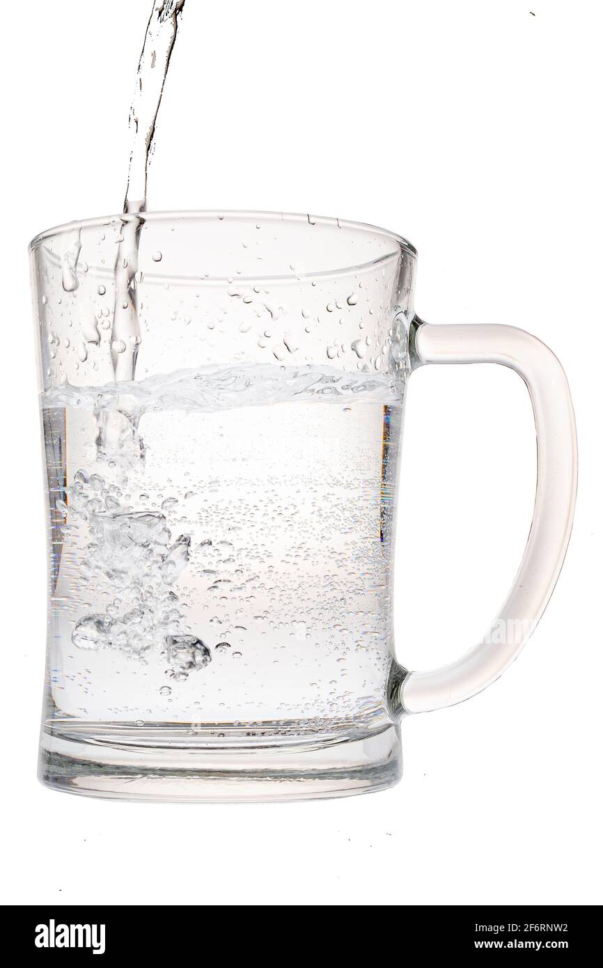 Pouring water into a glass mug. Fresh water in a glass container. Light ...