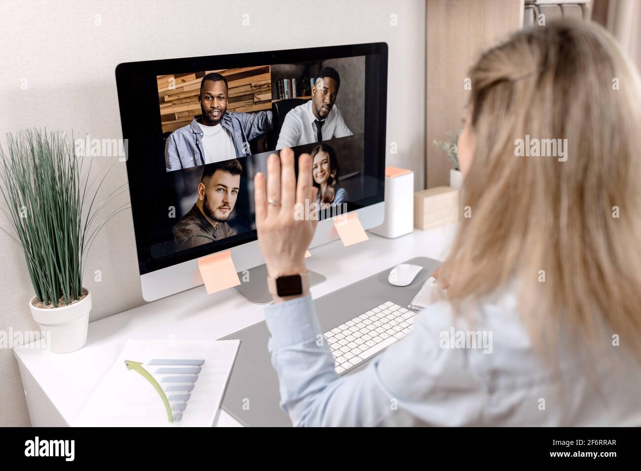 Back view of successful business waving hello to colleagues on video ...