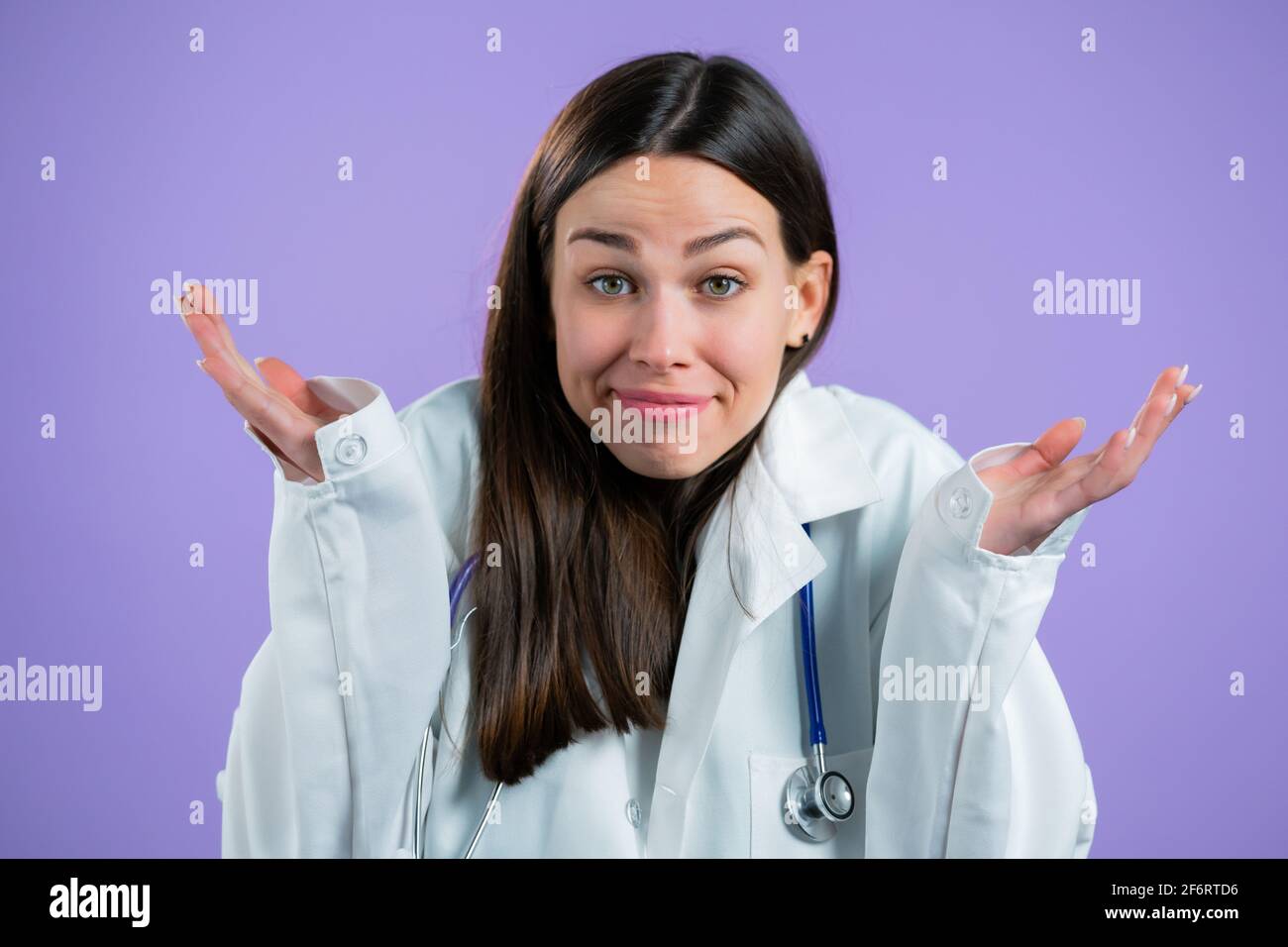 Unsure doctor woman in medical coat shrugs her arms, makes gesture of I ...