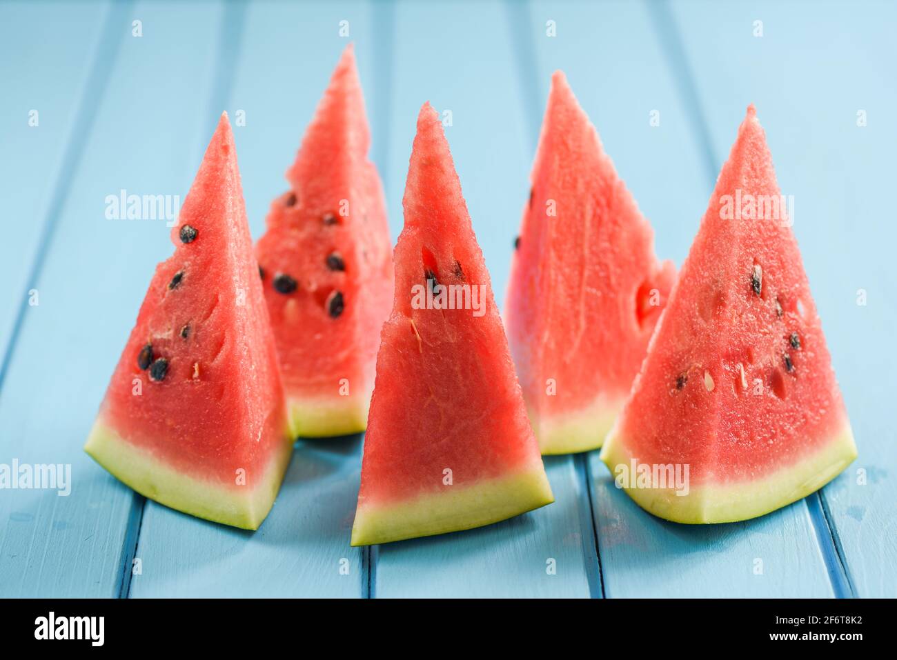 Fresh juicy watermelon with seeds cut into triangles on bright blue ...