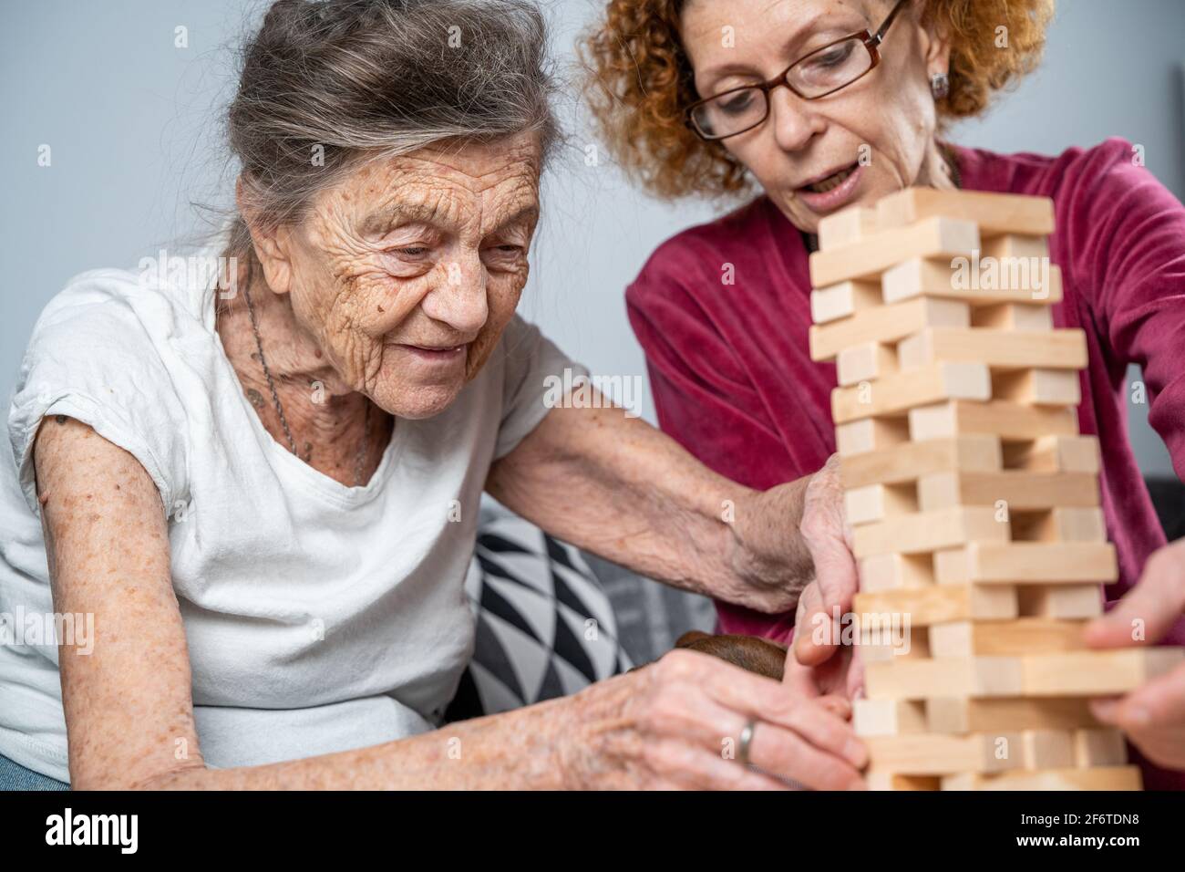 Retired mother and daughter spend time together at home, playing board ...