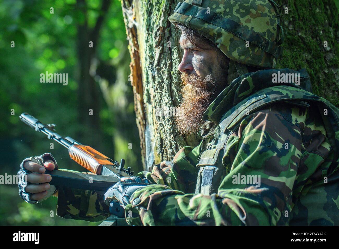 Soldier in military uniform and helmet with rifle on tree and green ...