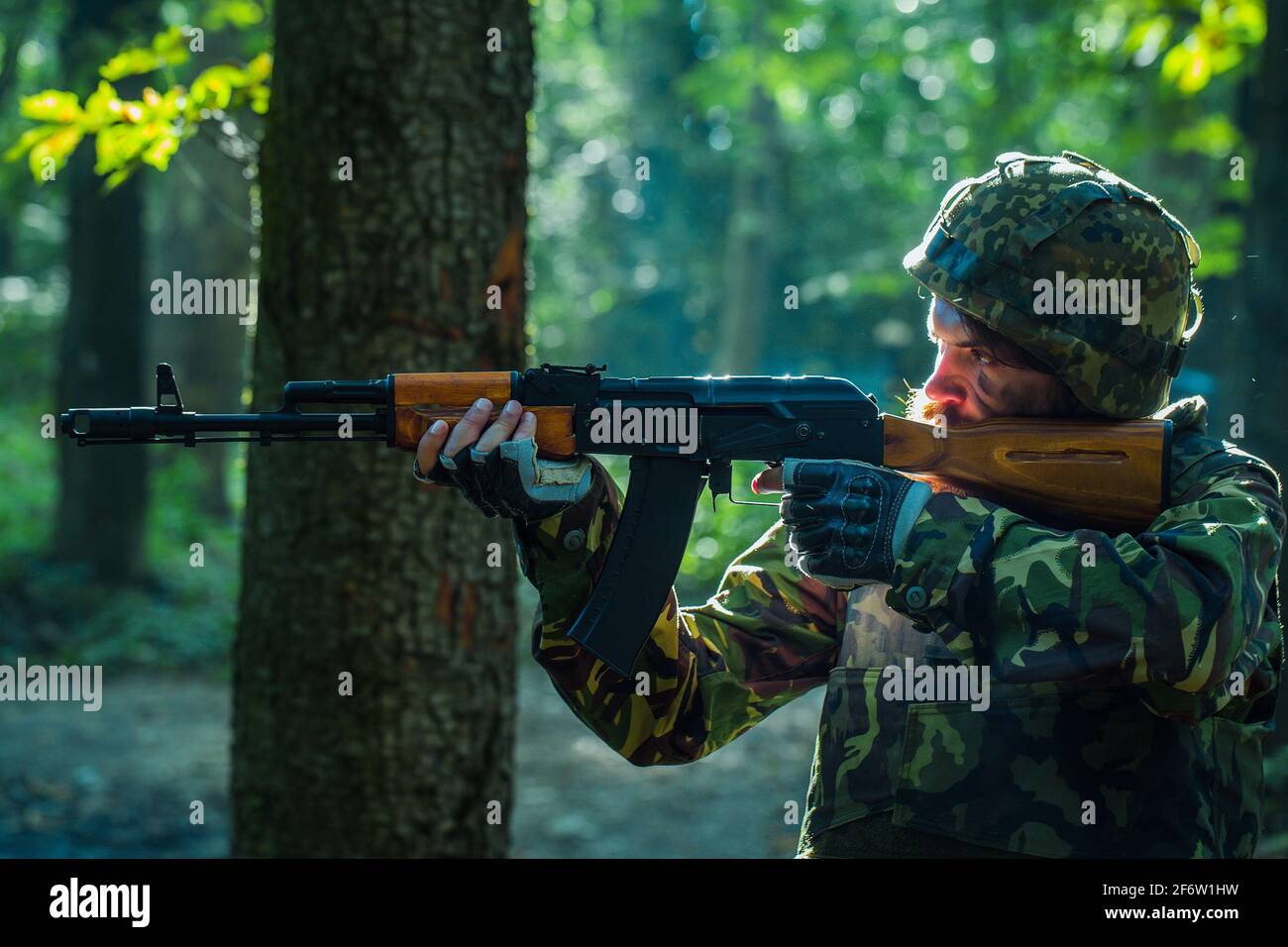 Sniper soldier in army ammunition camouflage and helmet holding rifle ...
