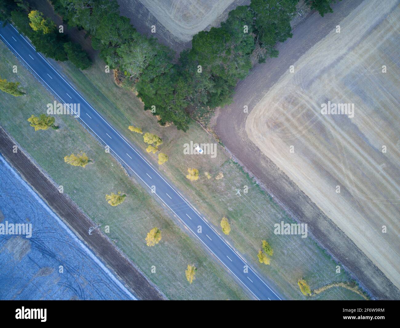 Country road Australia showing aerial farmland, lone car and trees in a ...