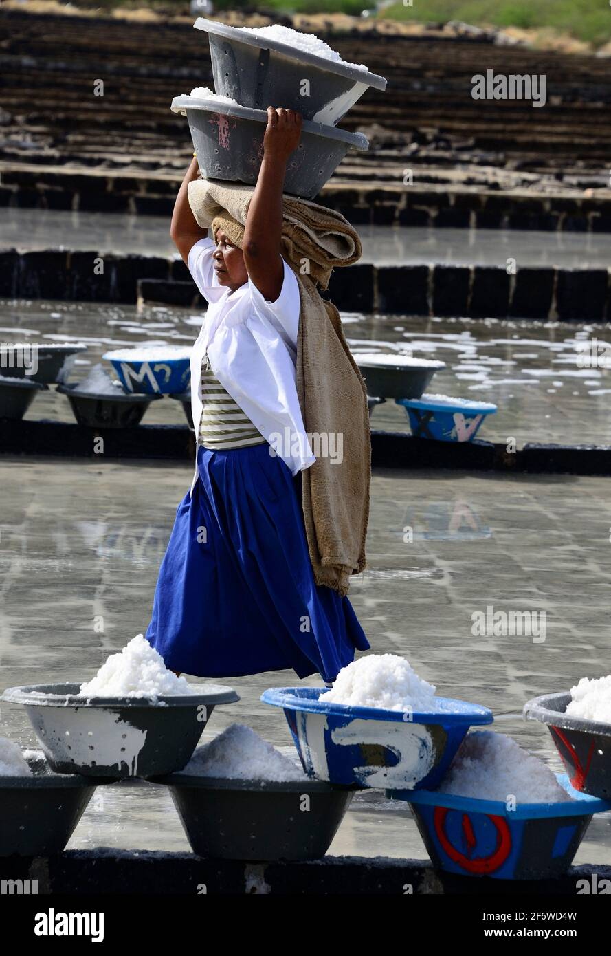 Traditional salt production, woman carrying a big, heavy bowl filled ...
