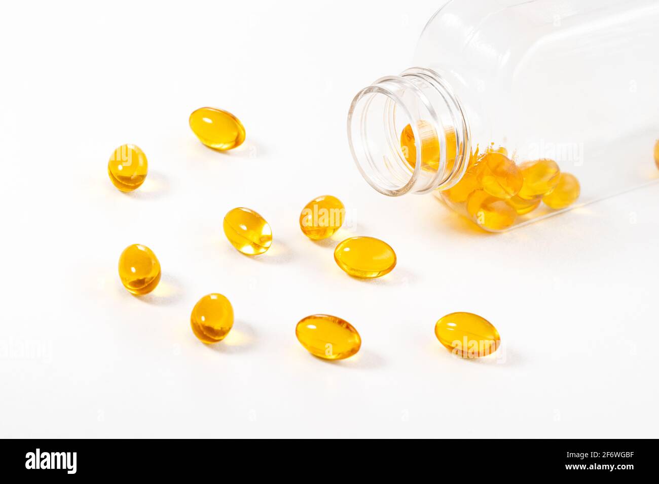 Yellow color fish oil capsules with glass bottle on white background ...
