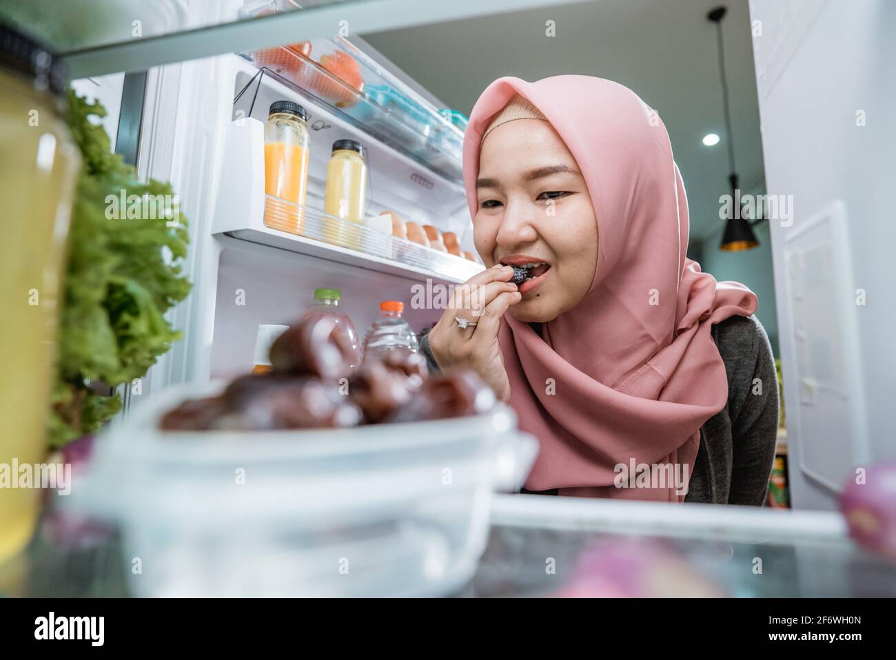 muslim asian woman eating dates fruit in the kitchen Stock Photo - Alamy