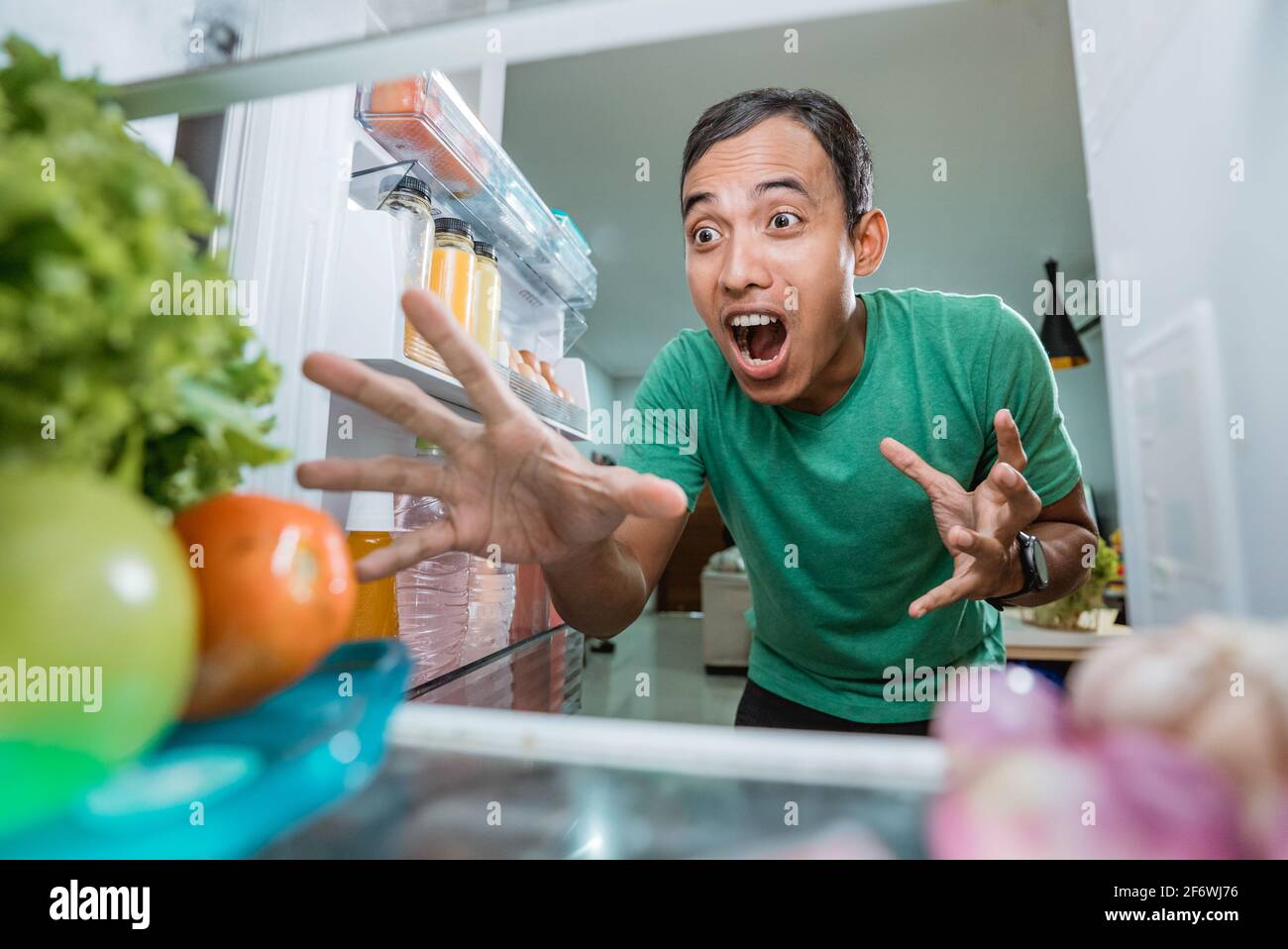 excited young asian man opening the fridge door Stock Photo - Alamy