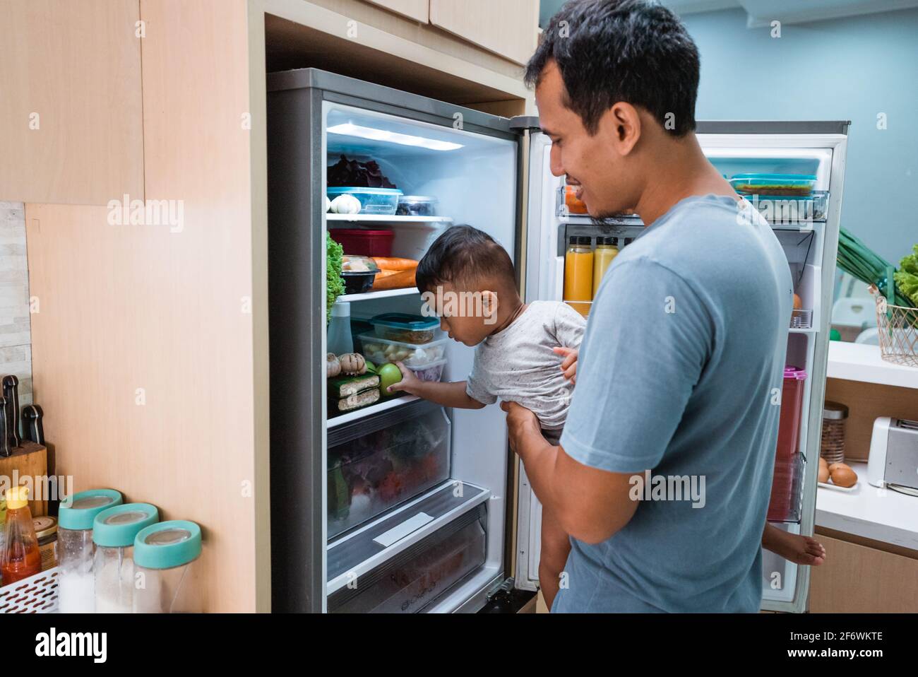 father and son open refrigerator at home looking for some food Stock ...
