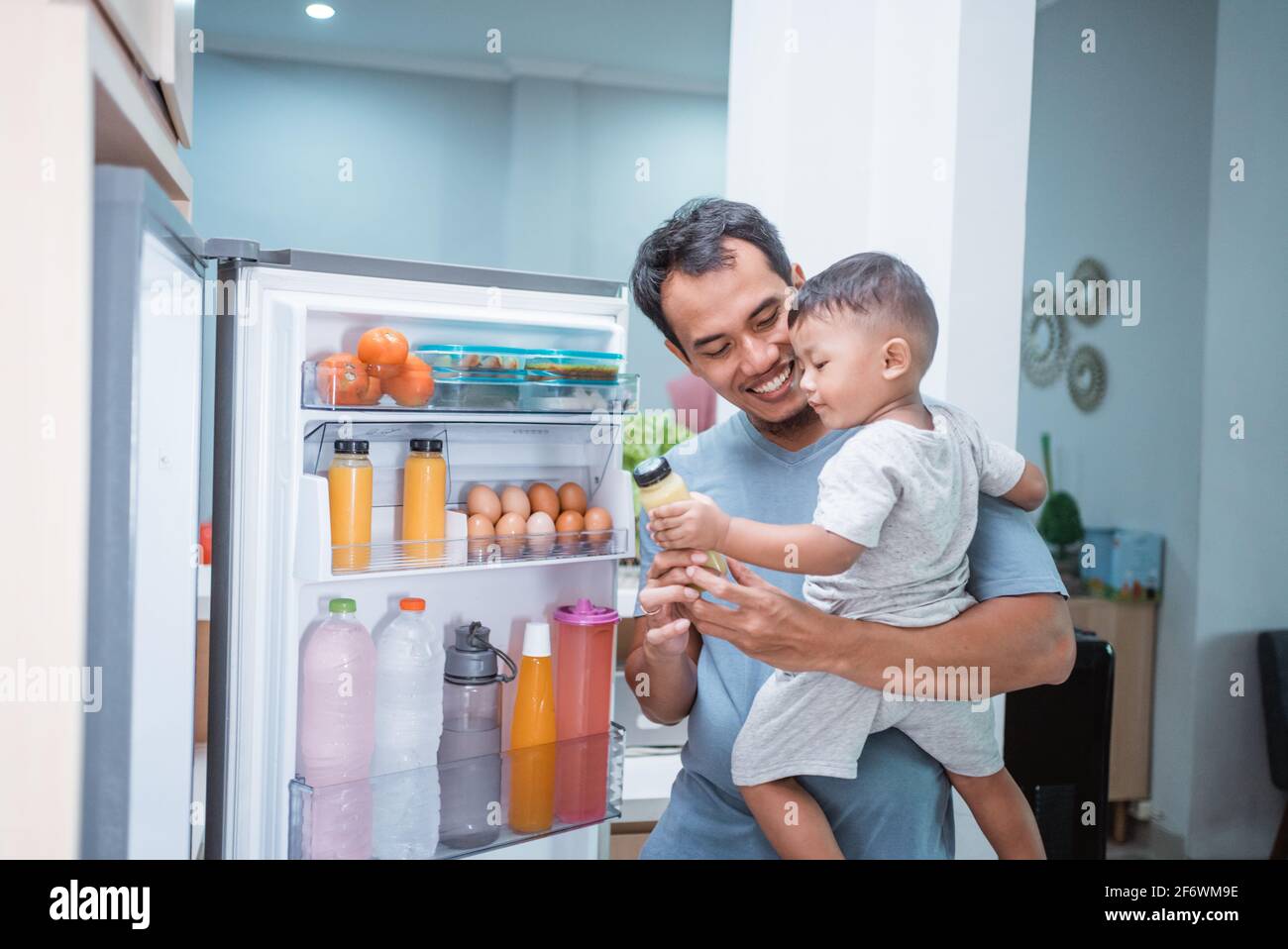 father and son open refrigerator at home looking for some food Stock ...