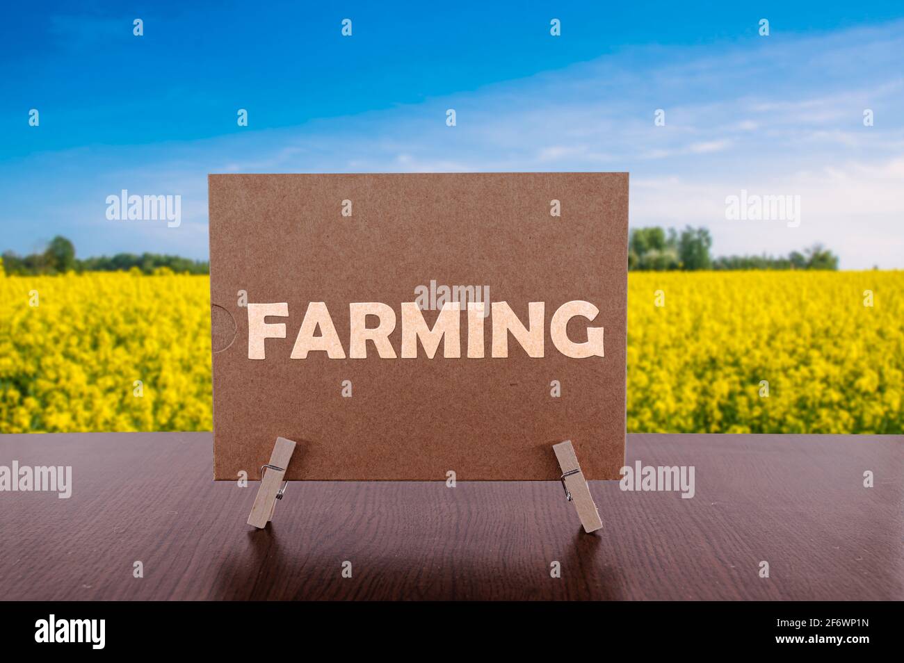 Farming text on card on the table with yellow field and blue sky ...
