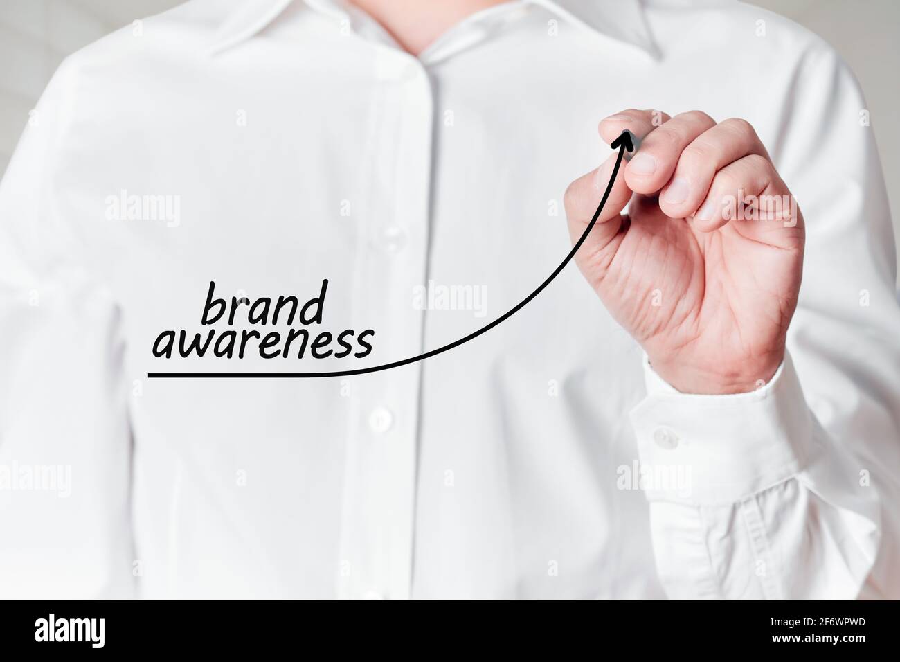 Businessman with pen draws a rising line graph with the word brand ...