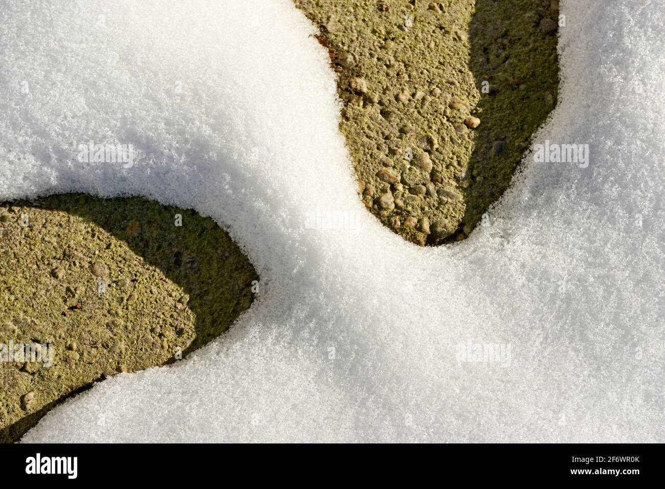 Melting snow on garden stone tile in winter. Spring or climate change ...