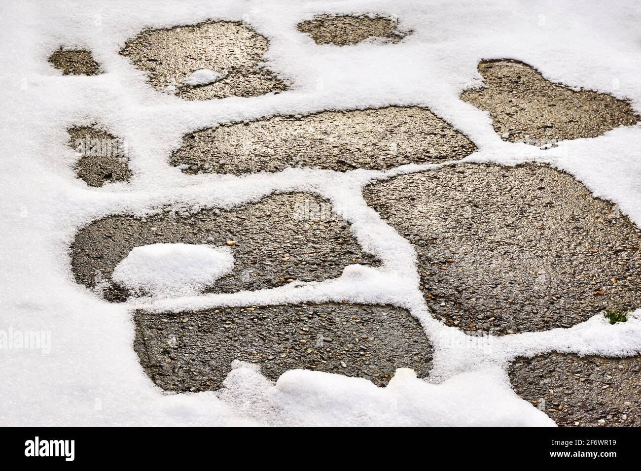 Melting snow on garden stone tiles in winter. Spring or climate change ...