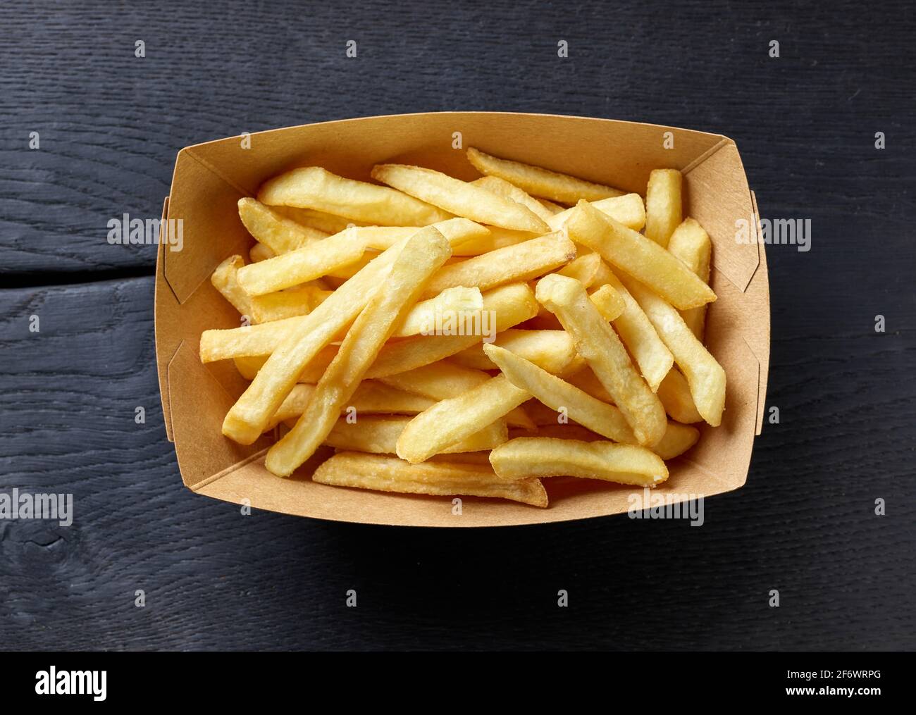 french fries in cardboard container on black wooden table, top view ...