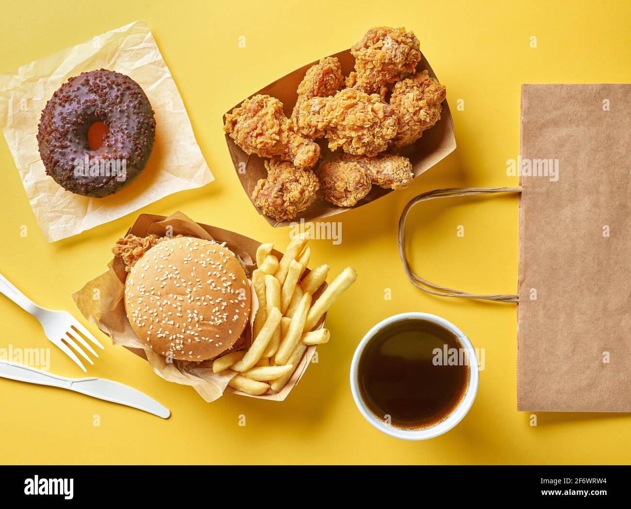 various fast food products and paper shopping bag on yellow background ...